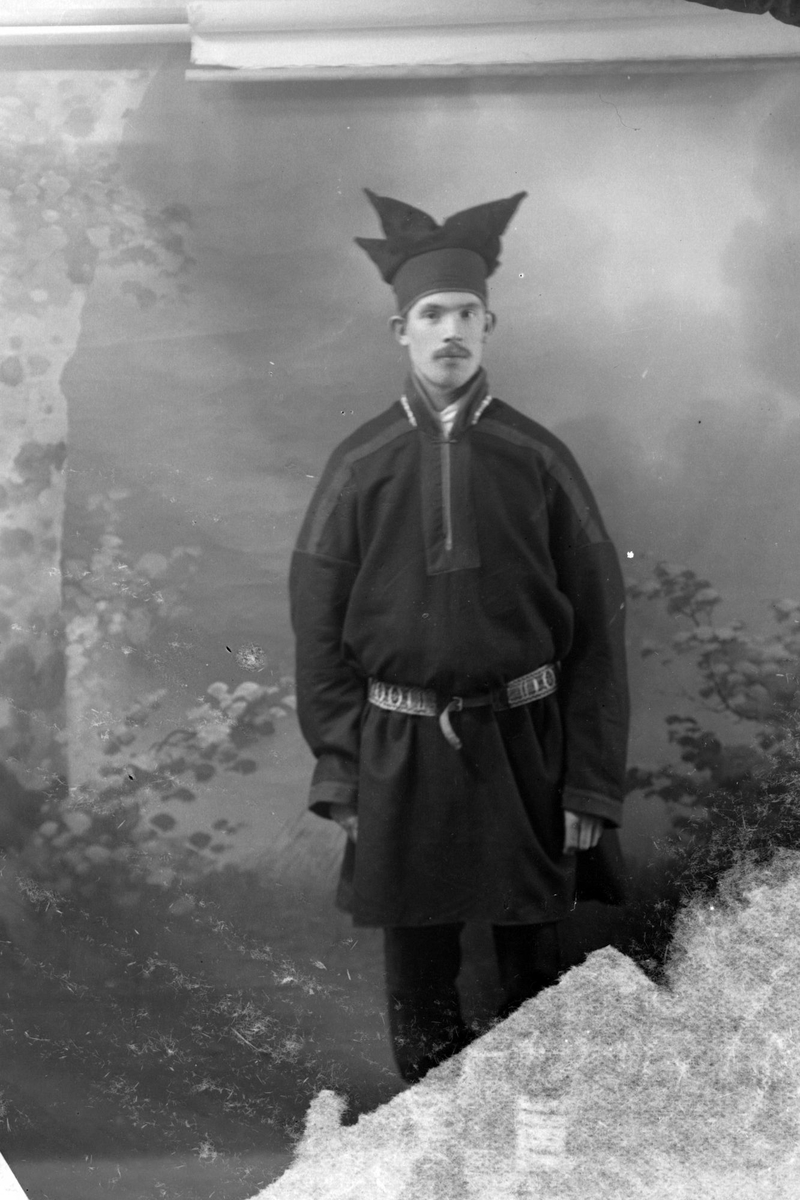 Studioportrett av en mann i samisk drakt med firevindslue på hodet ...