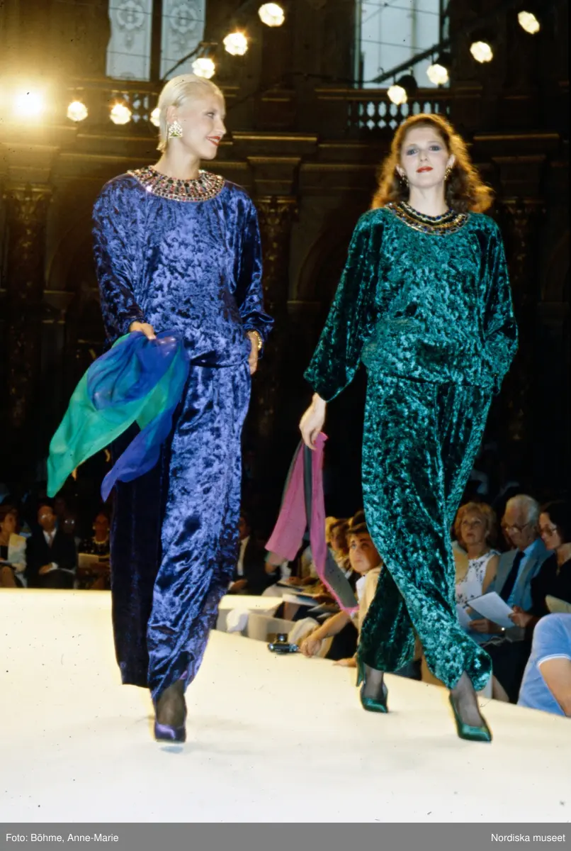 Modevisning. Två modeller i byxor och tröjor i krossad sammet i blått ...