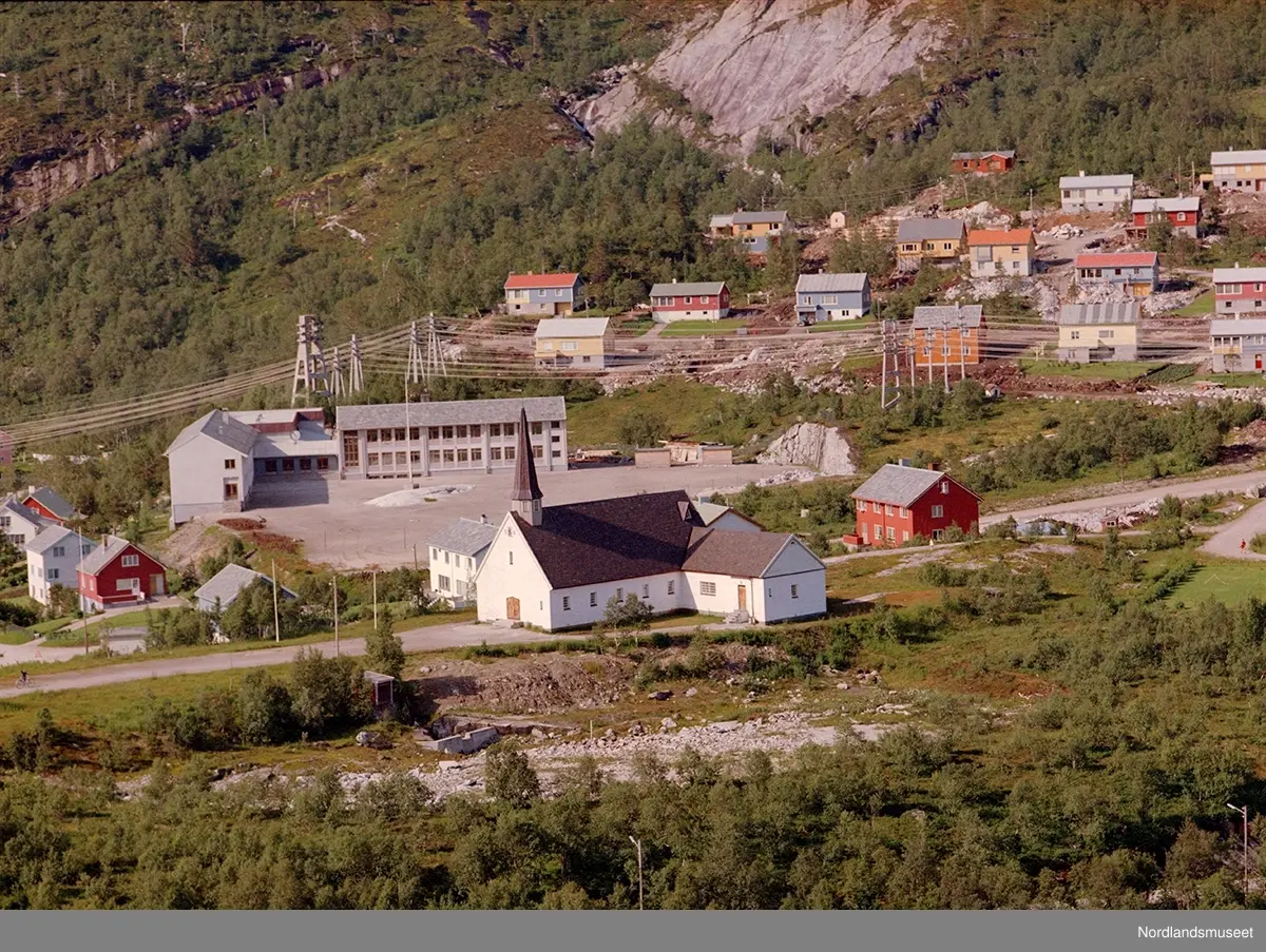flyfoto av Glomfjord kirke, Glomfjord skole i bakgrunn ...