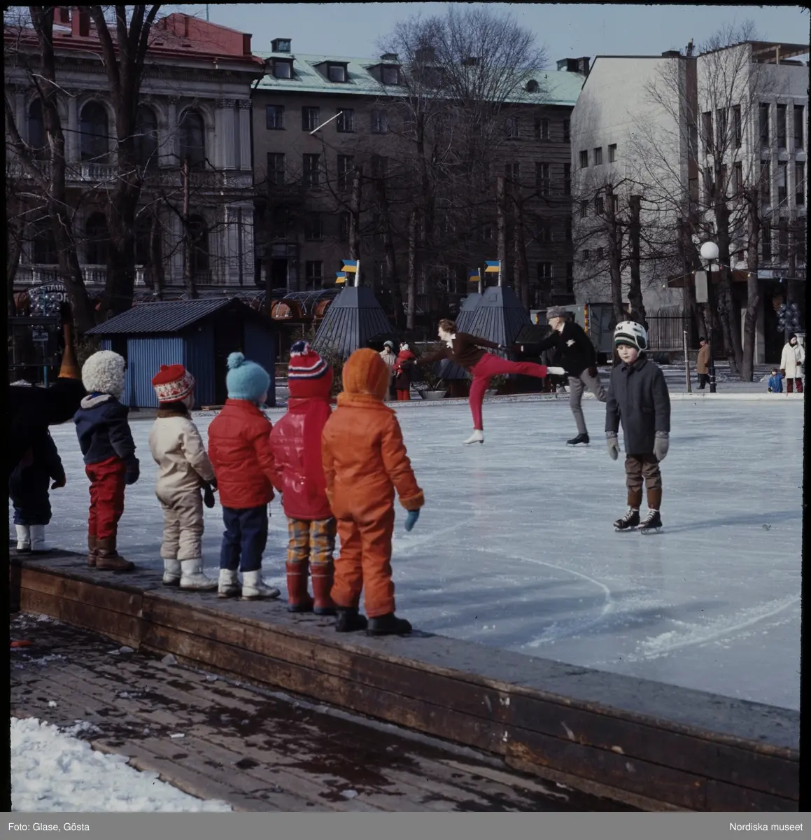 Barn betraktar skridskoåkare på isbanan i Kungsträdgården, Stockholm ...