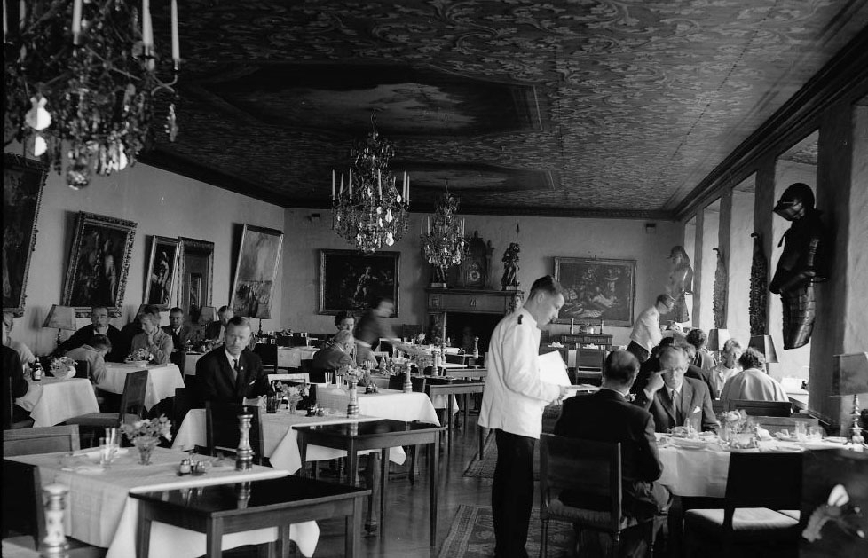 Matsalen till hotell/restaurang Gyllene Uttern med gäster. En servitör ...