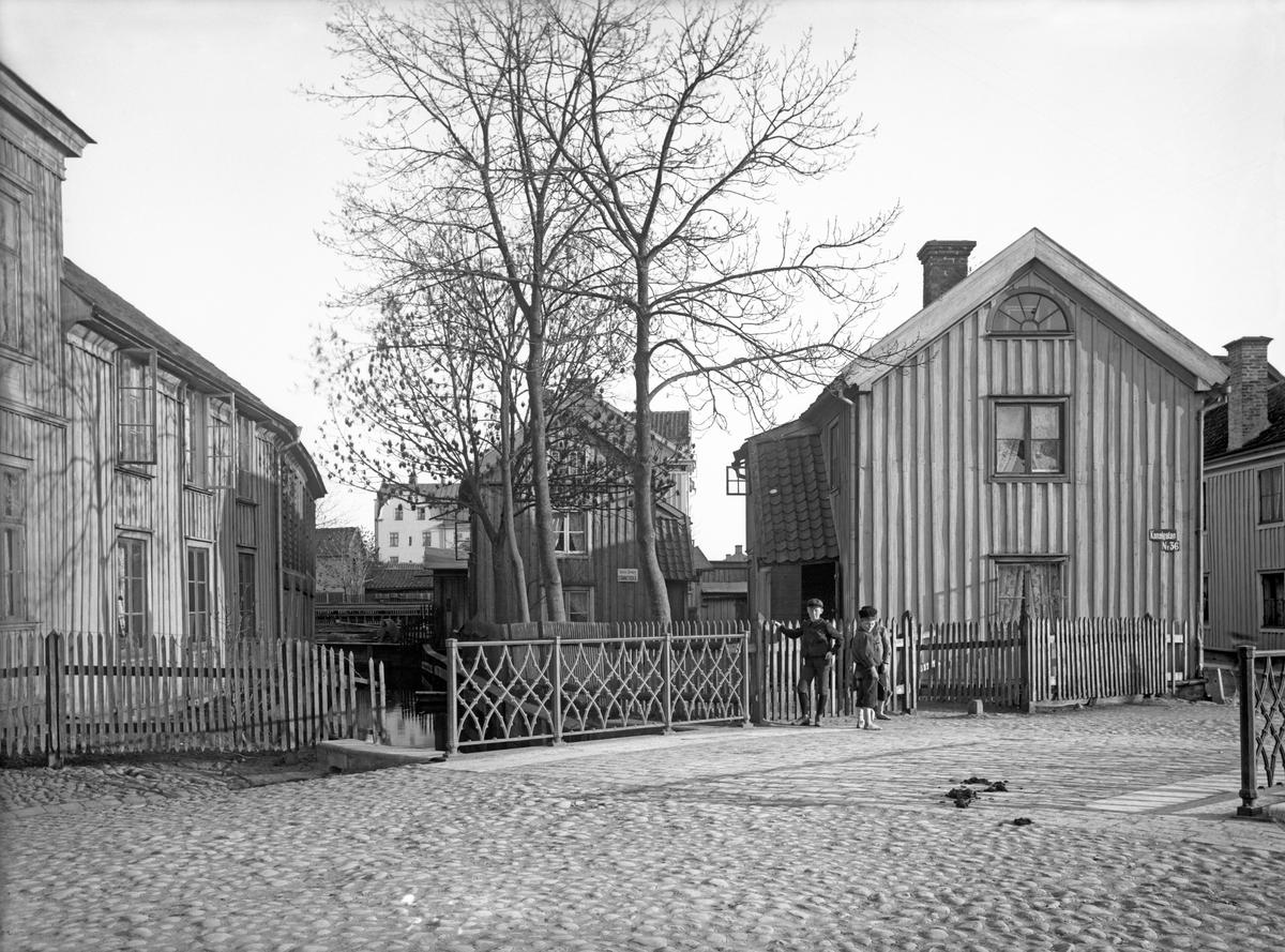 Kanalgatan 36 i Jönköping. Bro över kanalen som skymtas. Tre barn står ...