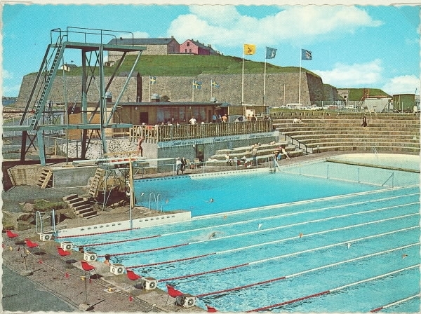 Simstadion i Varberg med fästningen i bakgrunden. Vykort, kolorerat ...