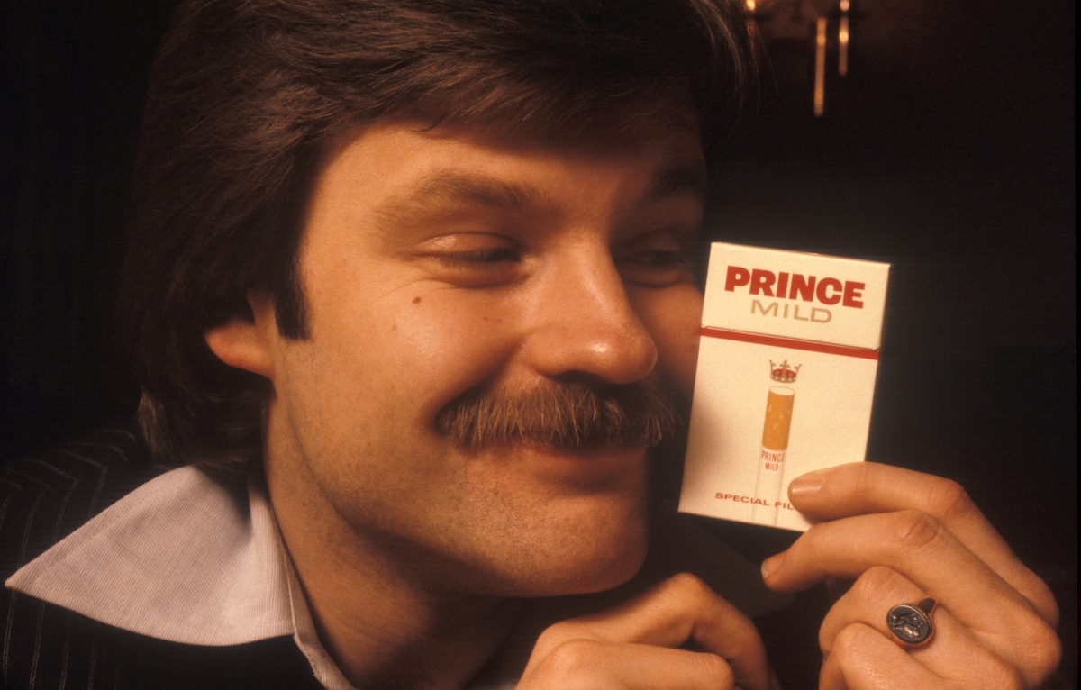 Reklamefoto av en mann som viser frem en pakke sigaretter av typen ...