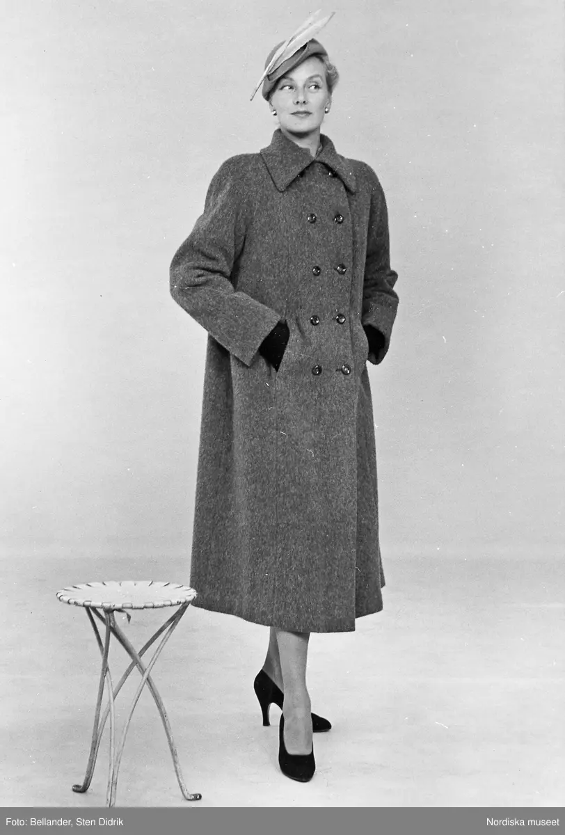 Modell i kappa, hatt med fjäderpenna och pumps, vid en pall. - Nordiska ...