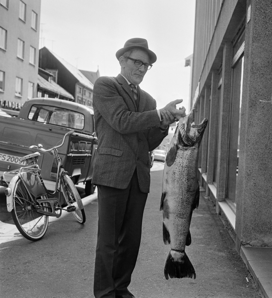 Stolt fisker med stor mjøsørret, som han løfter etter gjellelokkene ...